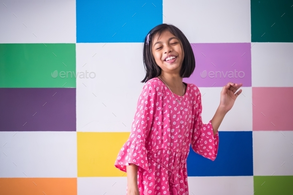 Little girl blushing and expressing happiness in front of a colourful ...