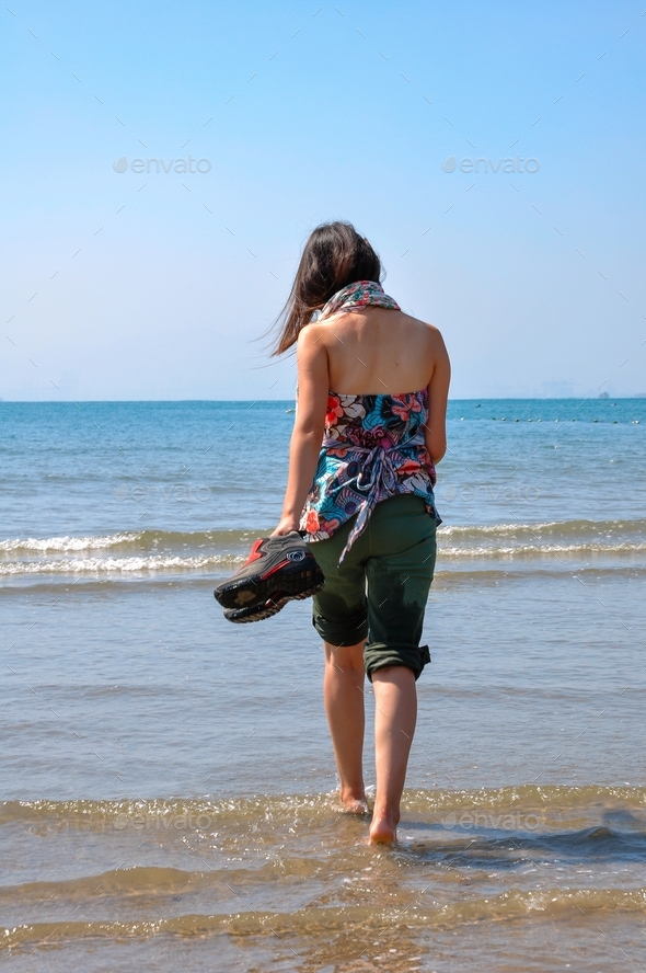 The graceful figure of a young lady walking into the sea. Tsingtao city ...