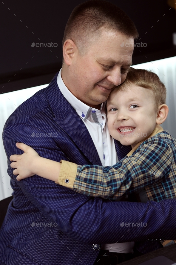 dad, a young man in an office suit hugs his son 6 years old Stock Photo ...
