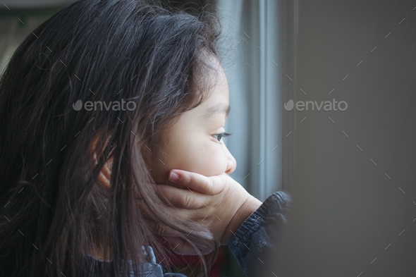A toddler girl looking out the window with her hand on her face. Bored, sad, longing, waiting ...