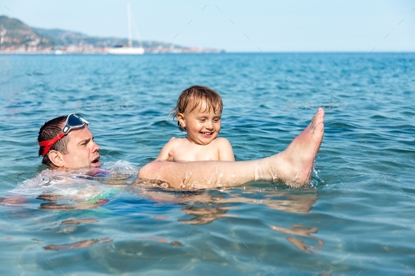 Father and little son having fun swimming and playing together in sea ...