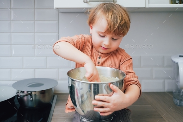 Cute blond preschool boy baking cake in domestic kitchen, indoors ...