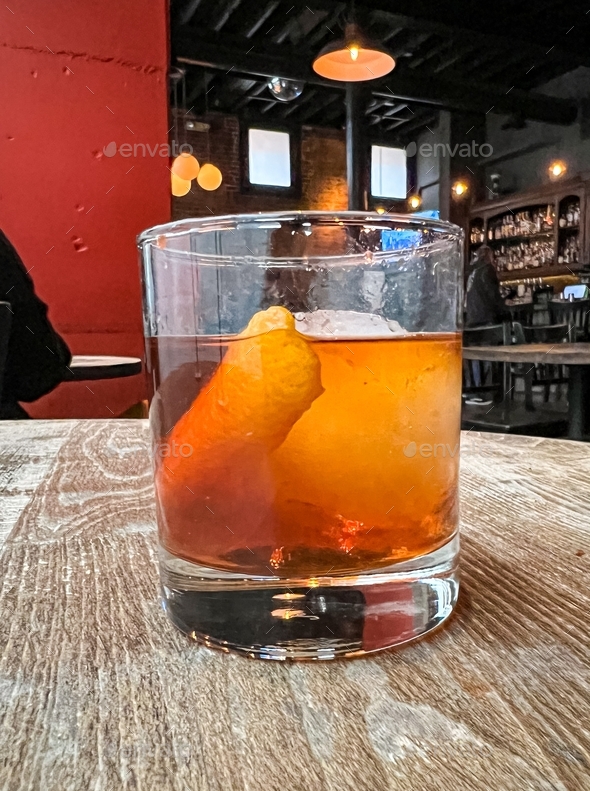 Old fashion whiskey drinks with sphere ice ball and orange peel inside ...