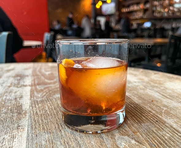 Old fashion whiskey drinks with sphere ice ball and orange peel inside ...