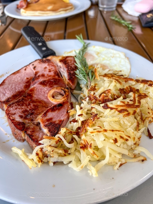 Grilled center cut ham steak, two eggs, hash browns breakfast on white ...