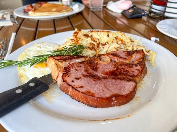 Grilled center cut ham steak, two eggs, hash browns breakfast on white ...