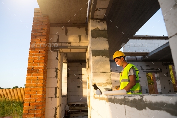 Construction engineer on the construction site of a house made of ...