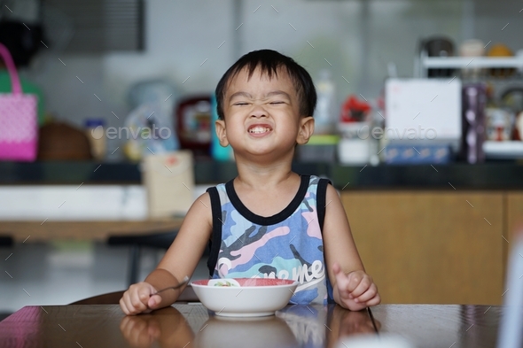 Smiley face of cute boy enjoys eating the food Stock Photo by phichatp