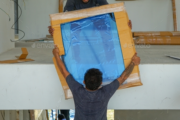 Back portrait worker delivering a frame of window for installation in ...