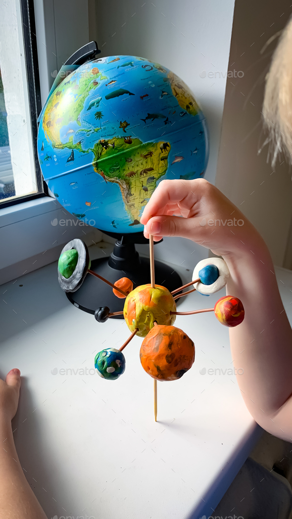 The child holds in his hands a model of the solar system, which he ...