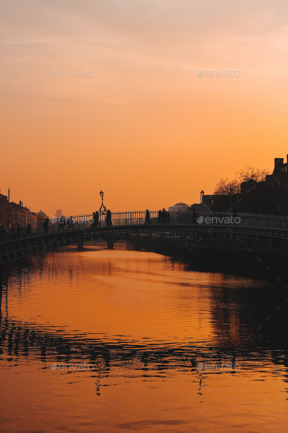 Intense orange sunset over the bridge and lind human shadows in front ...