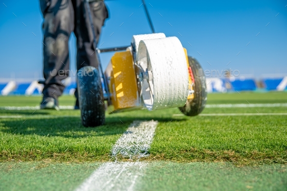 Lining a football pitch using white paint on grass. Stock Photo by Edovideo