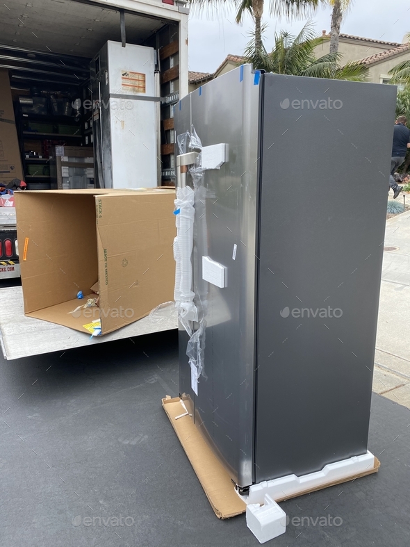 A new refrigerator arrives and is unwrapped in the street for delivery ...