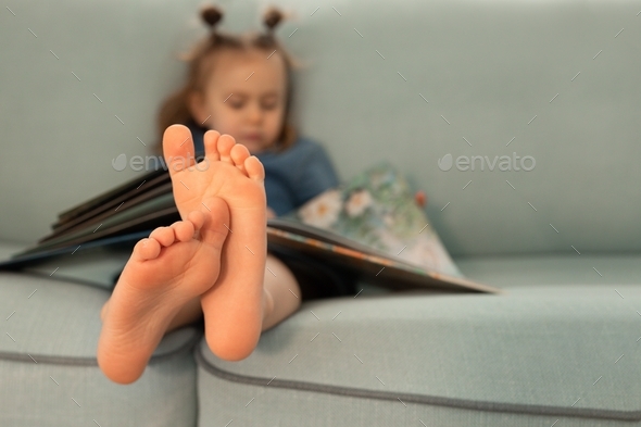 Child reading book on sofa, children feet close up Kid sleep and tired ...