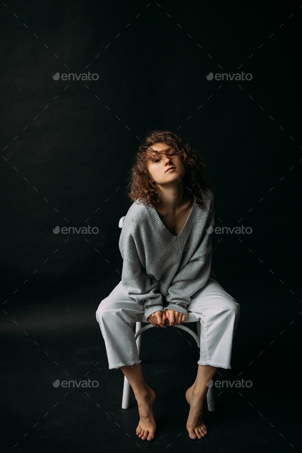 Curly girl sitting on the chair in confident position. Confident woman ...