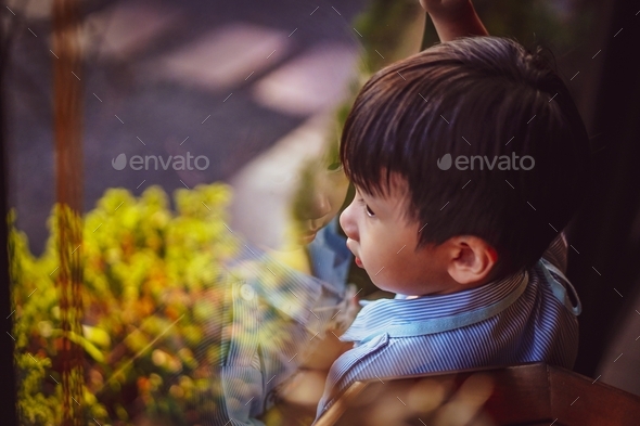 Cute little boy staring through window on a restaurant. Portraits of people thinking. Stock ...