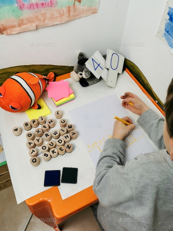 Preschool age boy writing the alphabet with colored yellow pencil ...