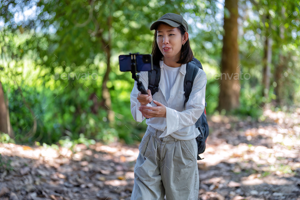 Young backpack hiking woman walking in the forest use mobile phone ...