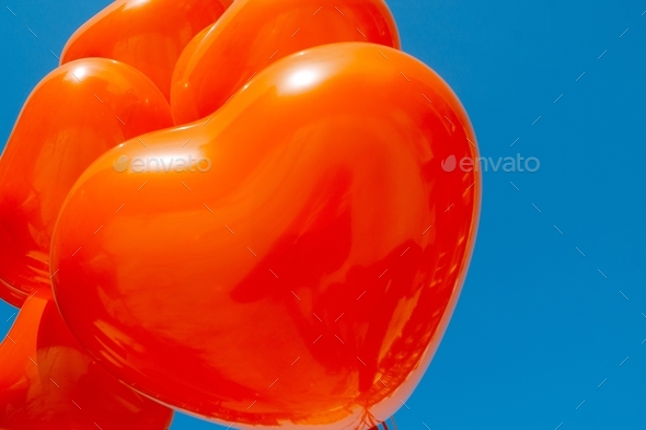 Orange heart-shaped balloons against a bright blue sky Stock Photo by ...