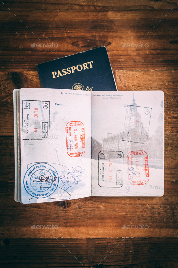 Flat lay of an open passport with stamps on top of a closed passport ...