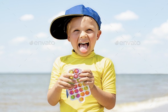 Funny child staying at the beach with simple dimple in his hands and ...