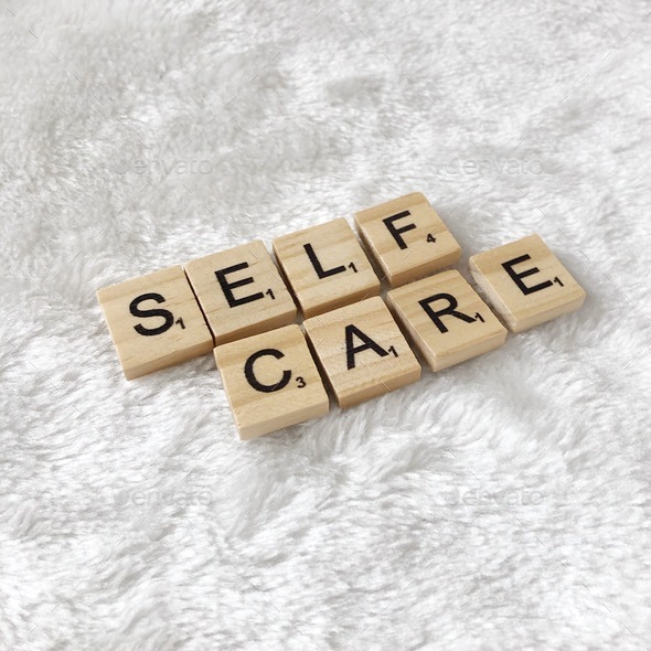 Self care written in wooden scrabble letter tiles on soft furry white ...