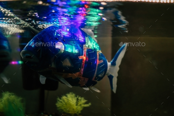 Partially blurred blue glowing large robot fish swimming underwater in ...