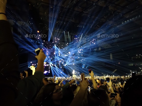 People holding up mobile cellphones using as lighters at a crowded ...