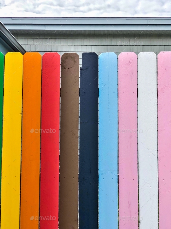 Colorful privacy picket fence surrounding house building home with tall ...