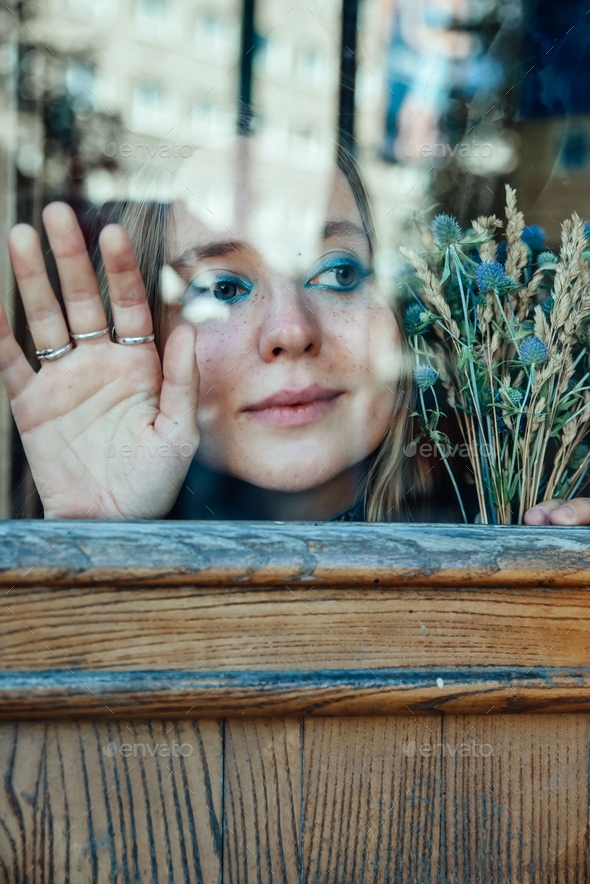 Young girl with big blue eyes outside the window.A touching waiting ...