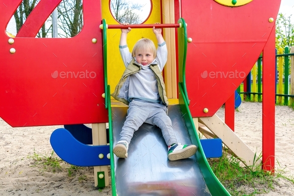 Cute funny smiling blonde little young toddler kid child boy going down ...