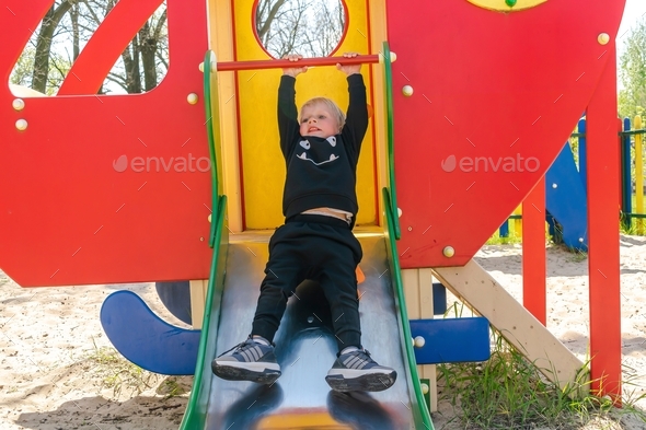 Cute funny smiling blonde little young toddler kid child boy going down ...