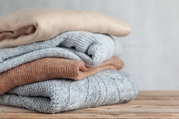 Stack of cozy knitted sweaters on a neutral background. Warm concept ...