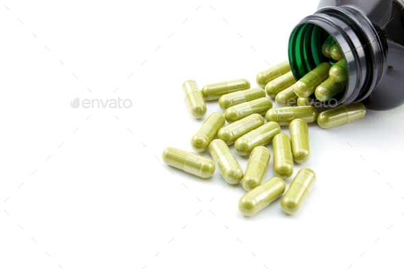 Herb capsule spilling out of bottle isolated on white. Stock Photo by ...