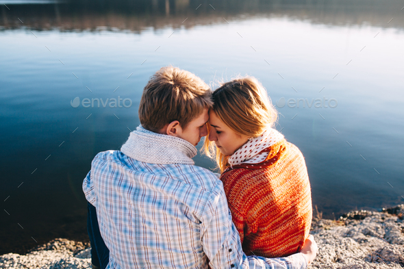 Back view of young couple cuddling near lake Stock Photo by kegfire