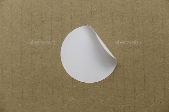 Blank white round stickers with folded corner on cardboard background ...