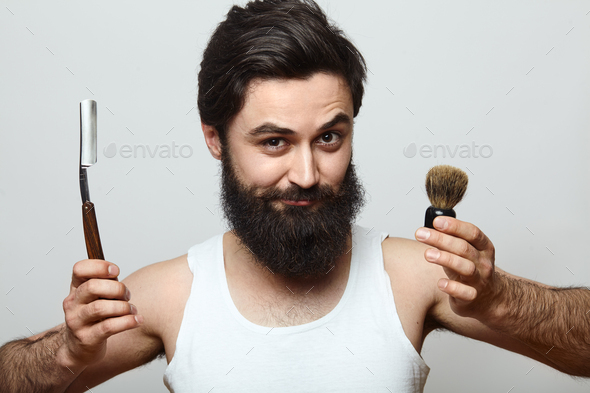 young funny man guy with beard showing razor blade Stock Photo by kegfire