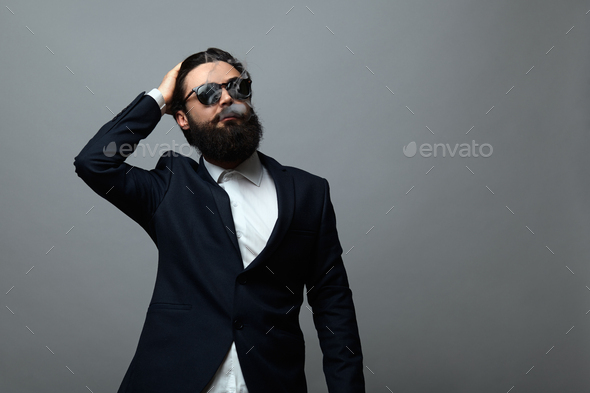 elegant business man fixing his hair over grey background Stock Photo ...