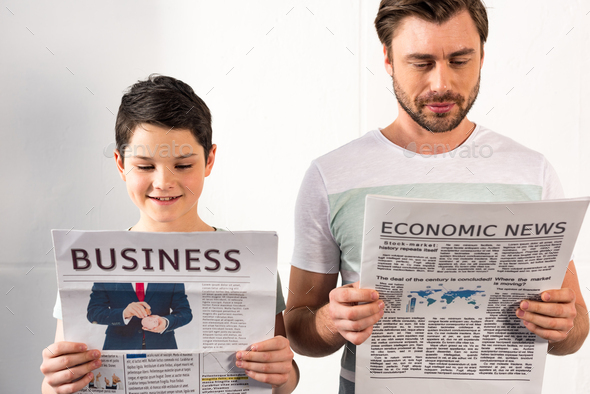 smiling son and concentrated father reading newspapers at home Stock ...