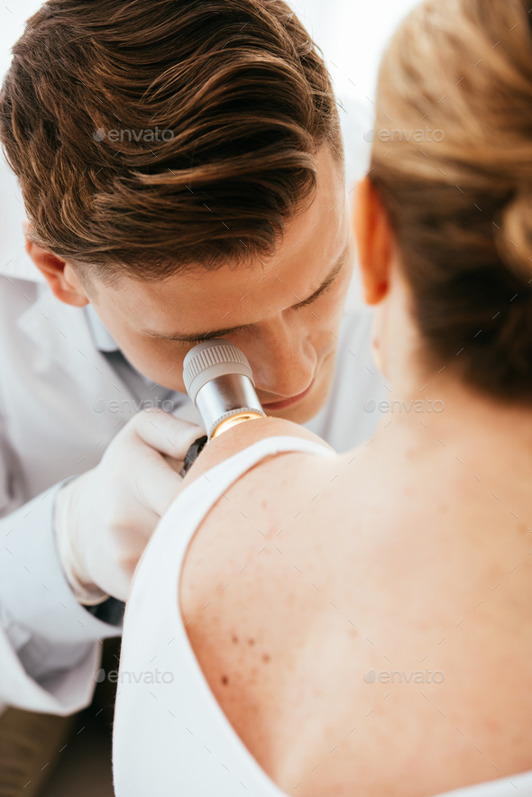 dermatologist holding dermatoscope while examining patient with skin ...