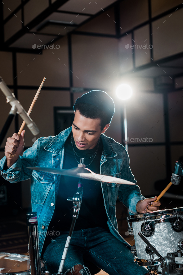 good-looking, inspired mixed race musician playing drums in recording ...