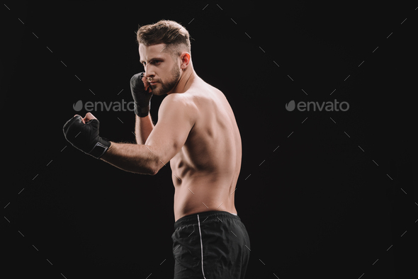 strong muscular mma fighter in bandages doing punch isolated on black ...