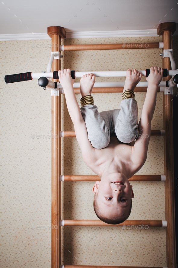 boy hanging upside down on a horizontal bar Stock Photo by zadveri