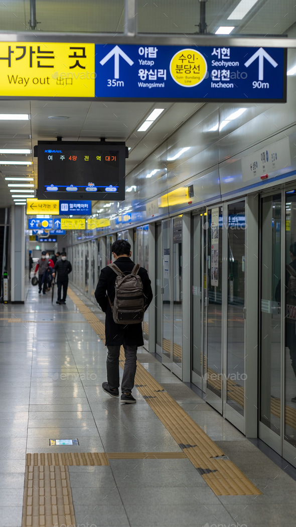 A guy walking and waiting for the train to arrive at a subway station ...