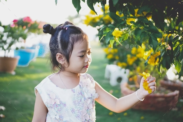 Side View Of Girl Plucking Flowers From Plant At Park Stock Photo by sboowj