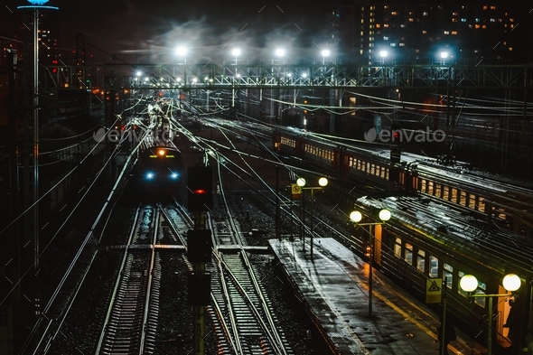 railway at night, city lanterns at the station, approaching train Stock Photo by shangarey