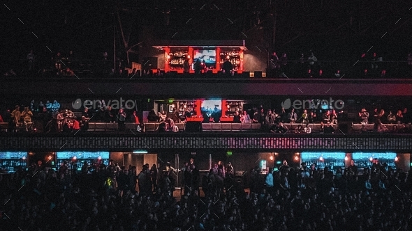 Balconies crowded with people and lit with neon lights and cast with ...