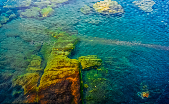 Turquoise blue green waters with algae covered rocks below the surface ...