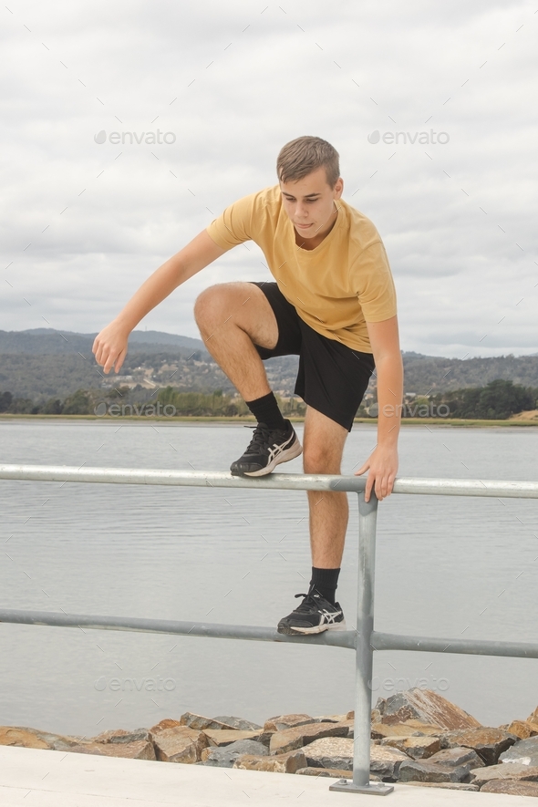 Teenage boy jumping off fence. Risk taking behaviour. Stock Photo by ...