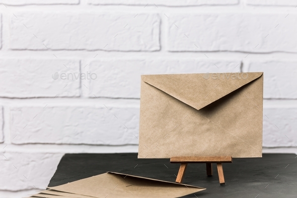 Blank envelope made of craft paper stands on a stand on a black table ...